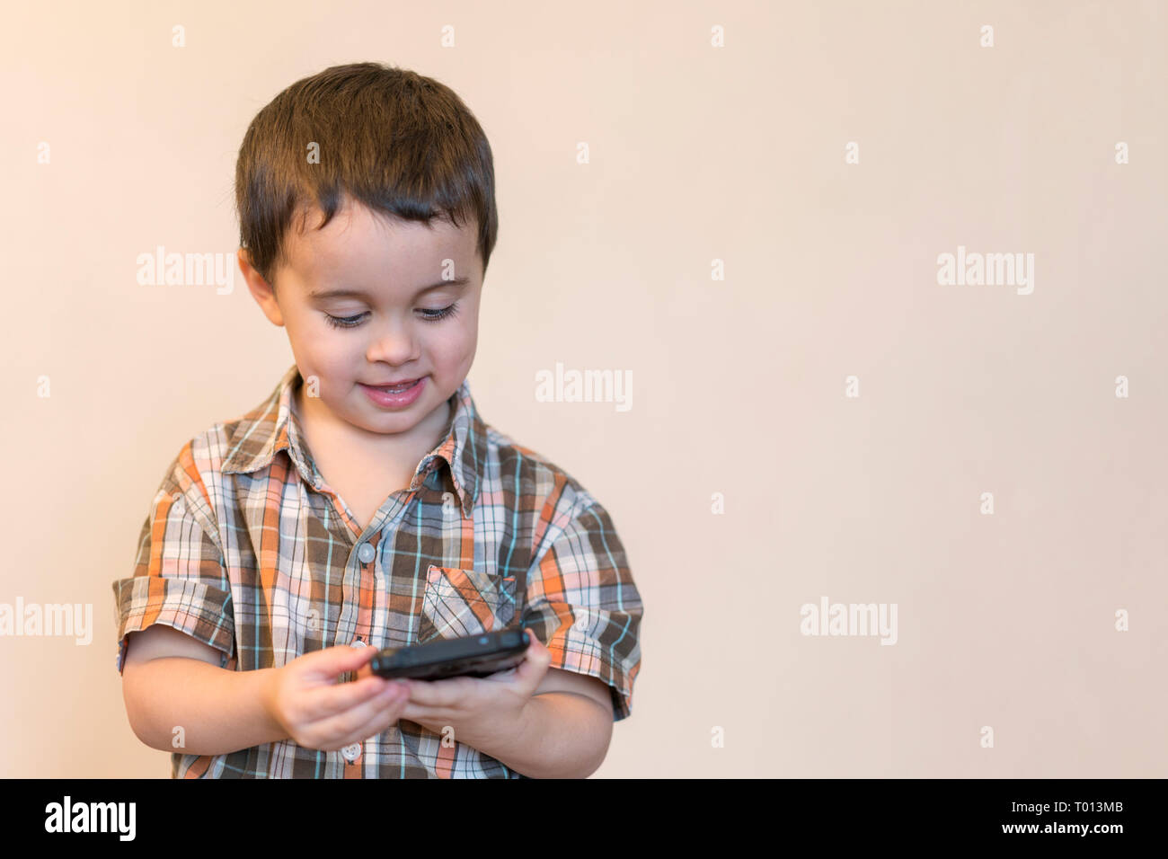 Portrait of a smiling little boy holding mobile phone isolated over ...