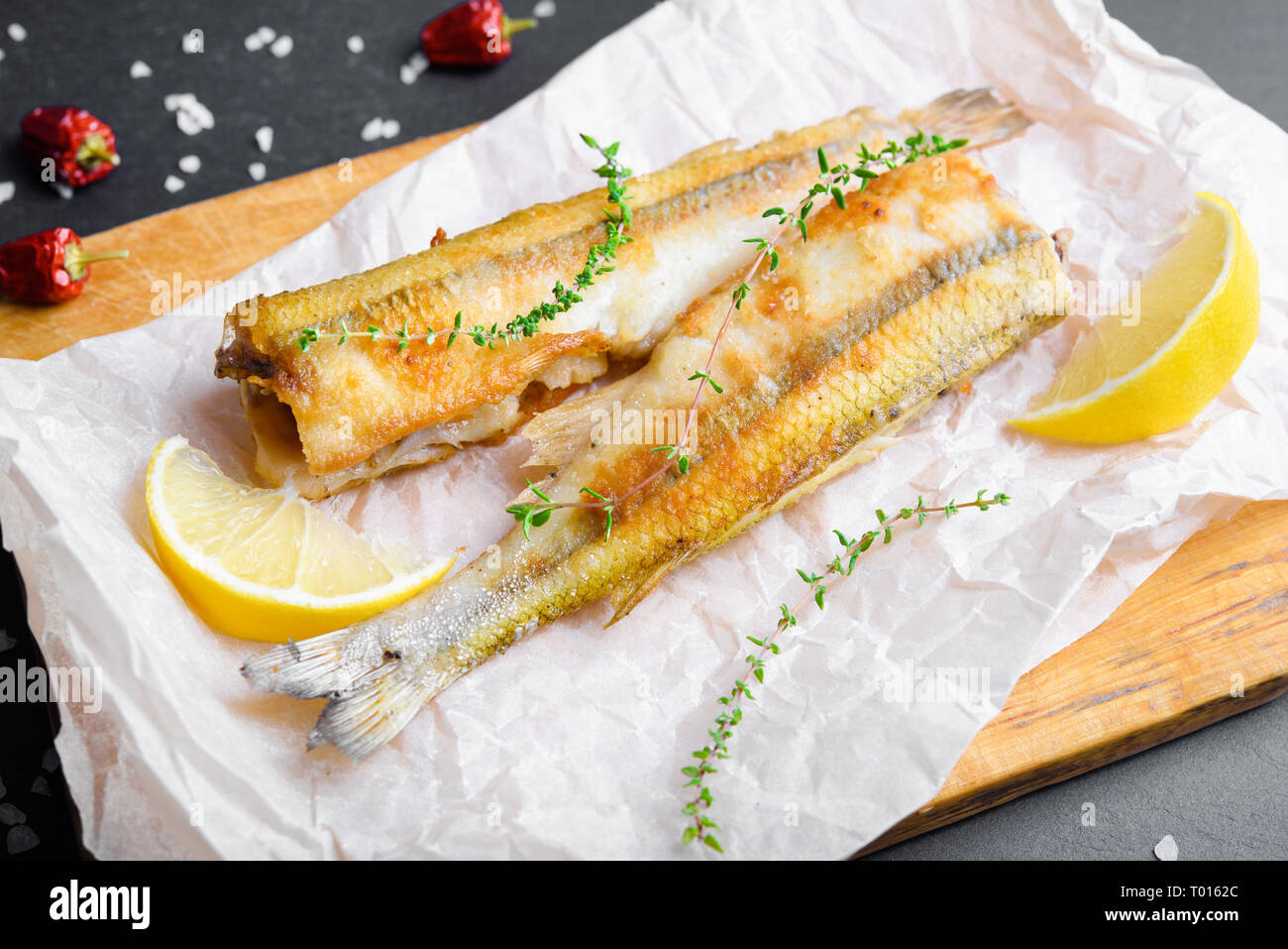 Two smelts fish on bake paper with lemon Stock Photo - Alamy