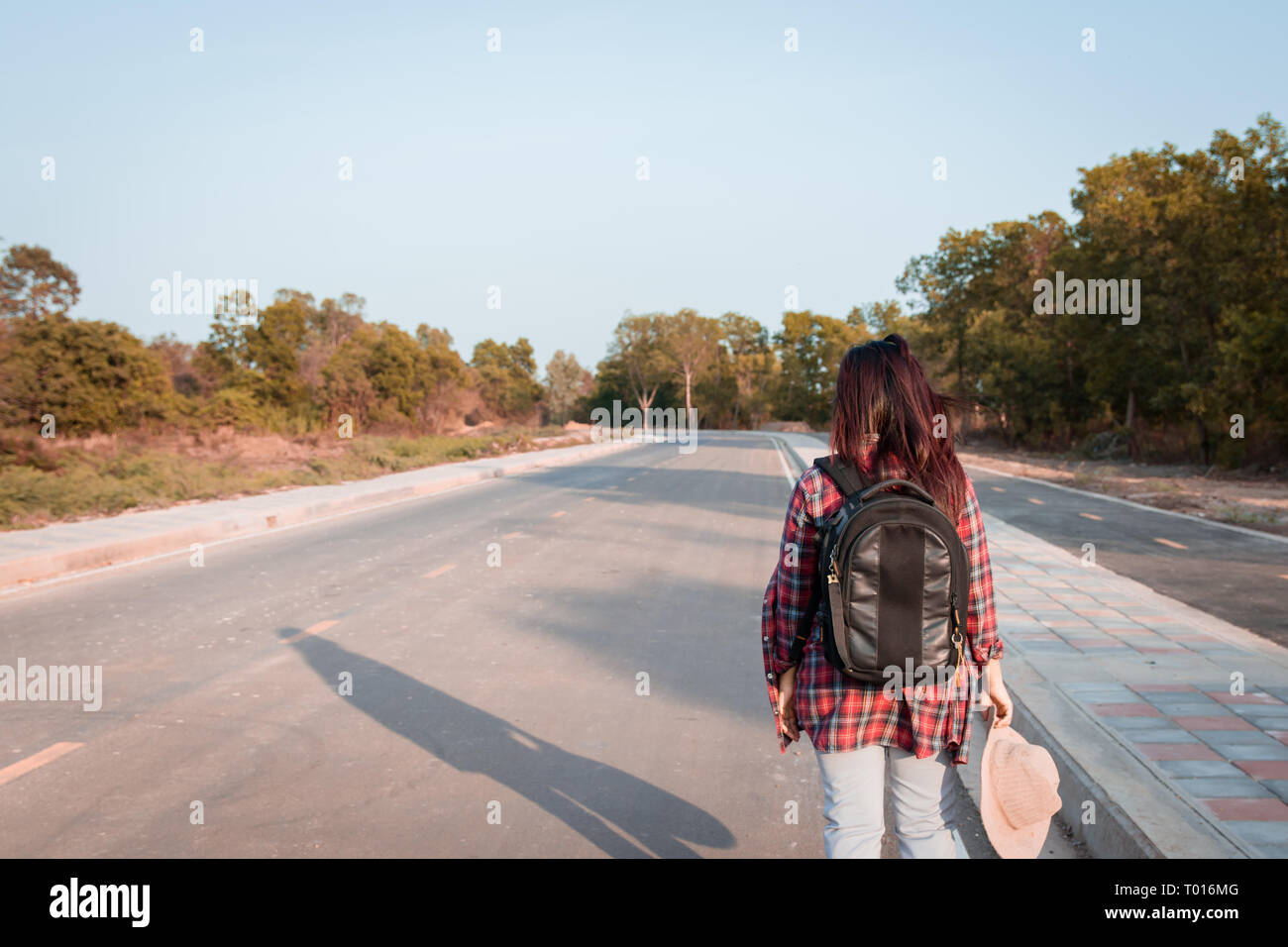 Travel concept. Traveling woman with backpack walking on asphalt road ...