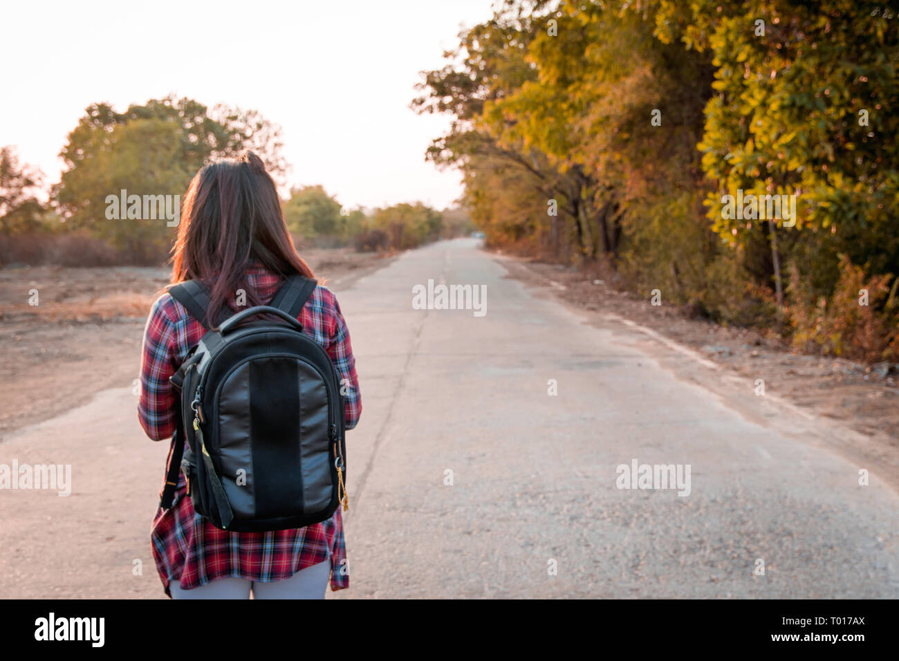 Travel concept. Traveling woman with backpack walking on asphalt road ...