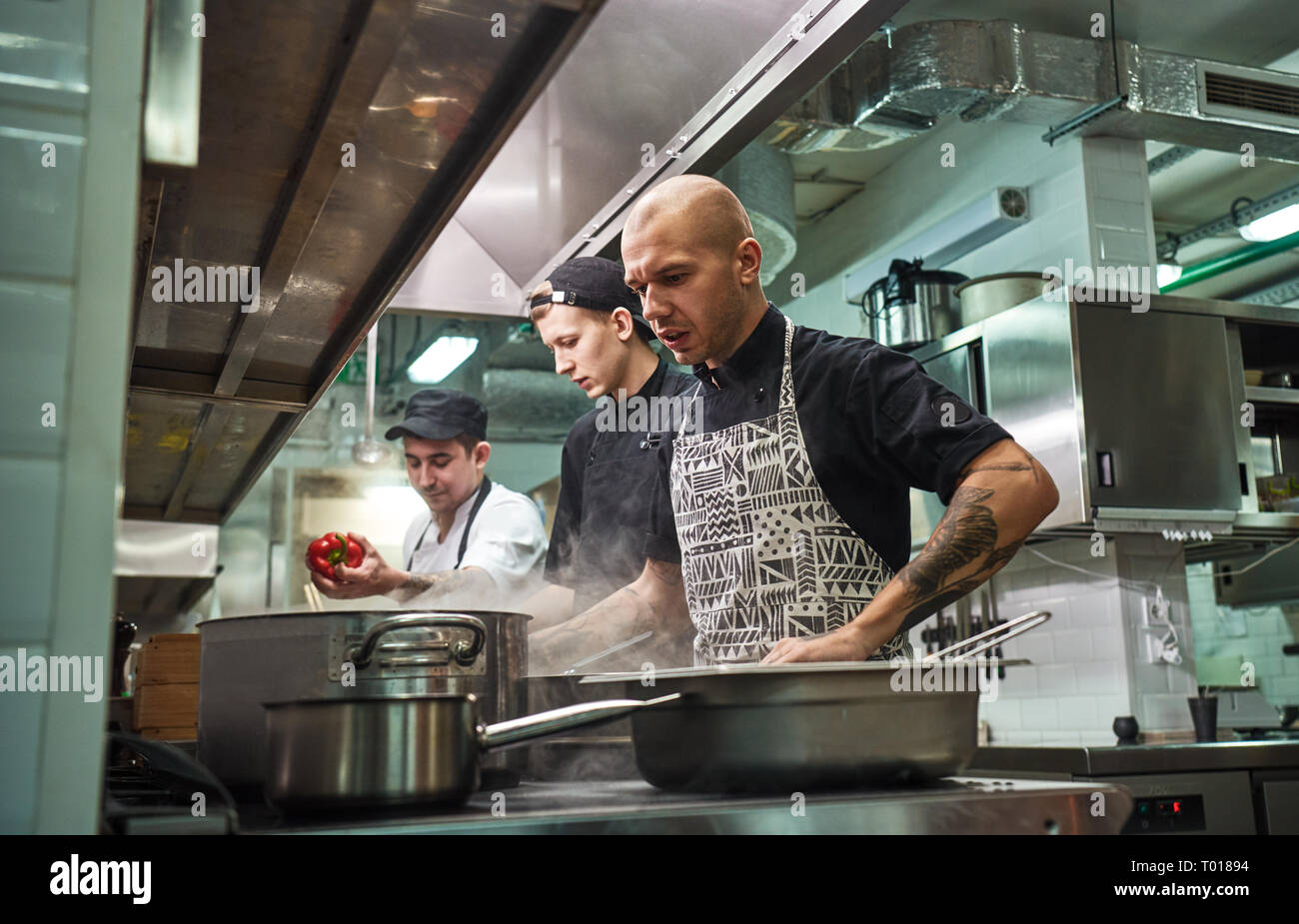 Concentrated at work. Professional team of chef and two young ...