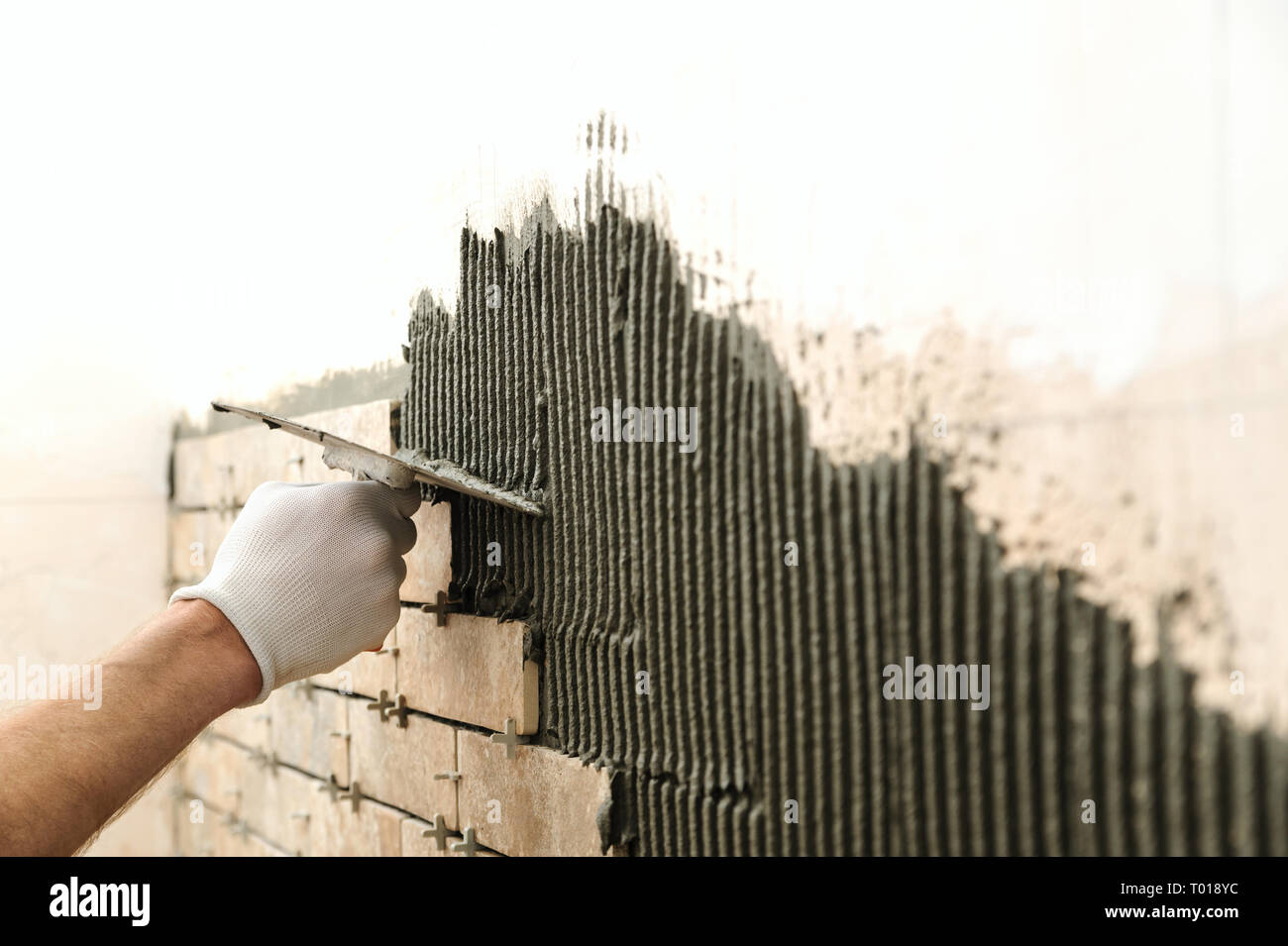 Installing the tiles on the wall. A worker setting tiles in the form of ...