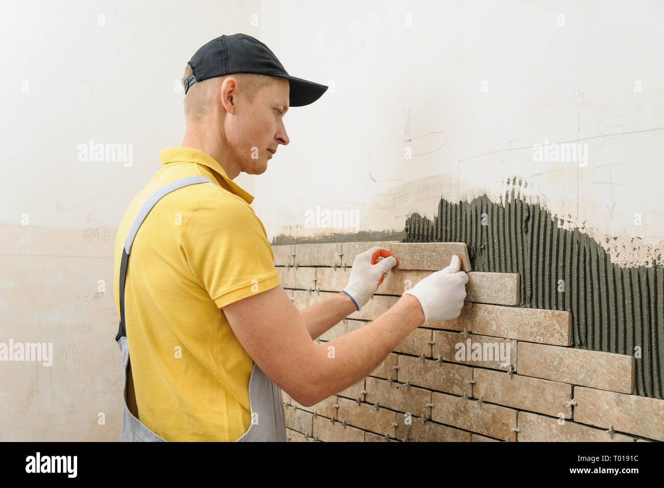 Installing the tiles on the wall. The worker putting tiles in the form ...