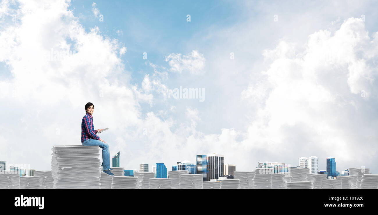 Attractive man sitting on pile of paper documents Stock Photo - Alamy