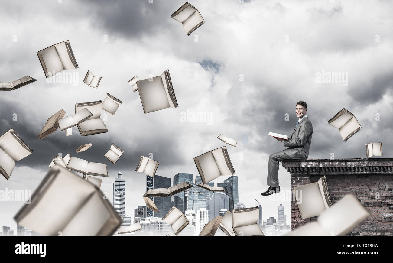 Man on roof reading book and many of them flying in air Stock Photo - Alamy