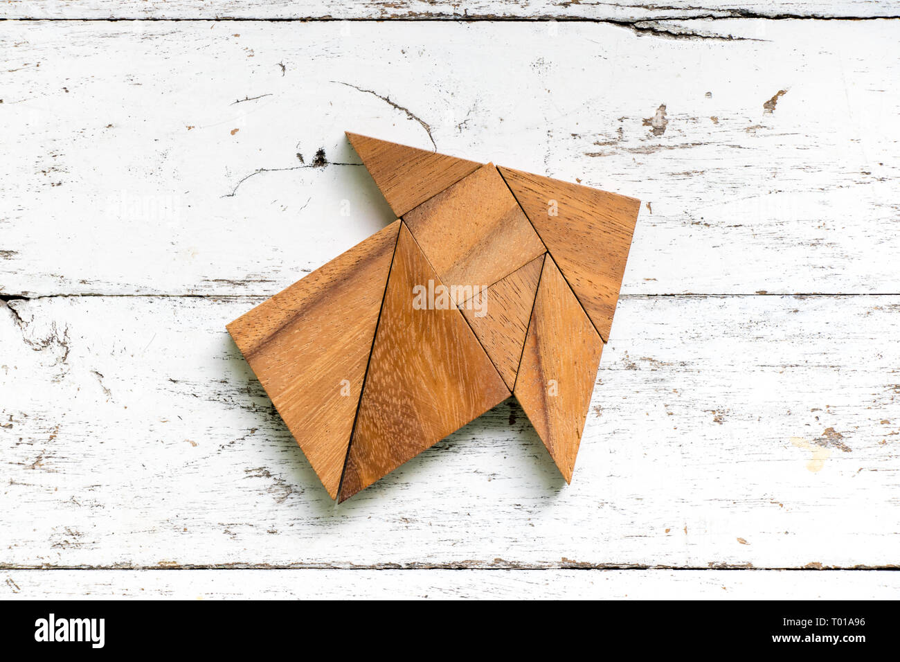 Tangram puzzle in direction arrow shape on old white wood background ...
