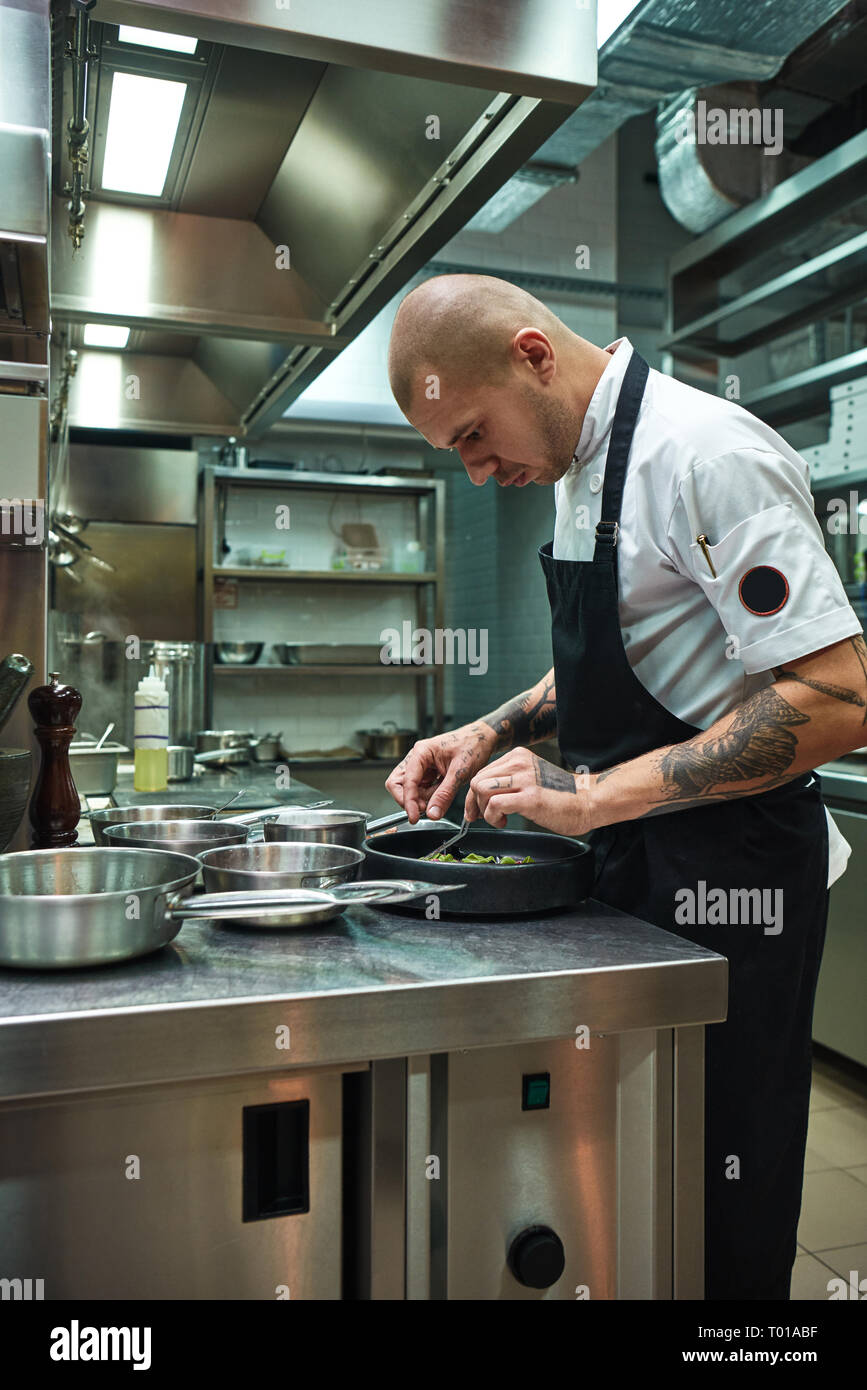 Last details. Side view of confident male chef in black apron ...