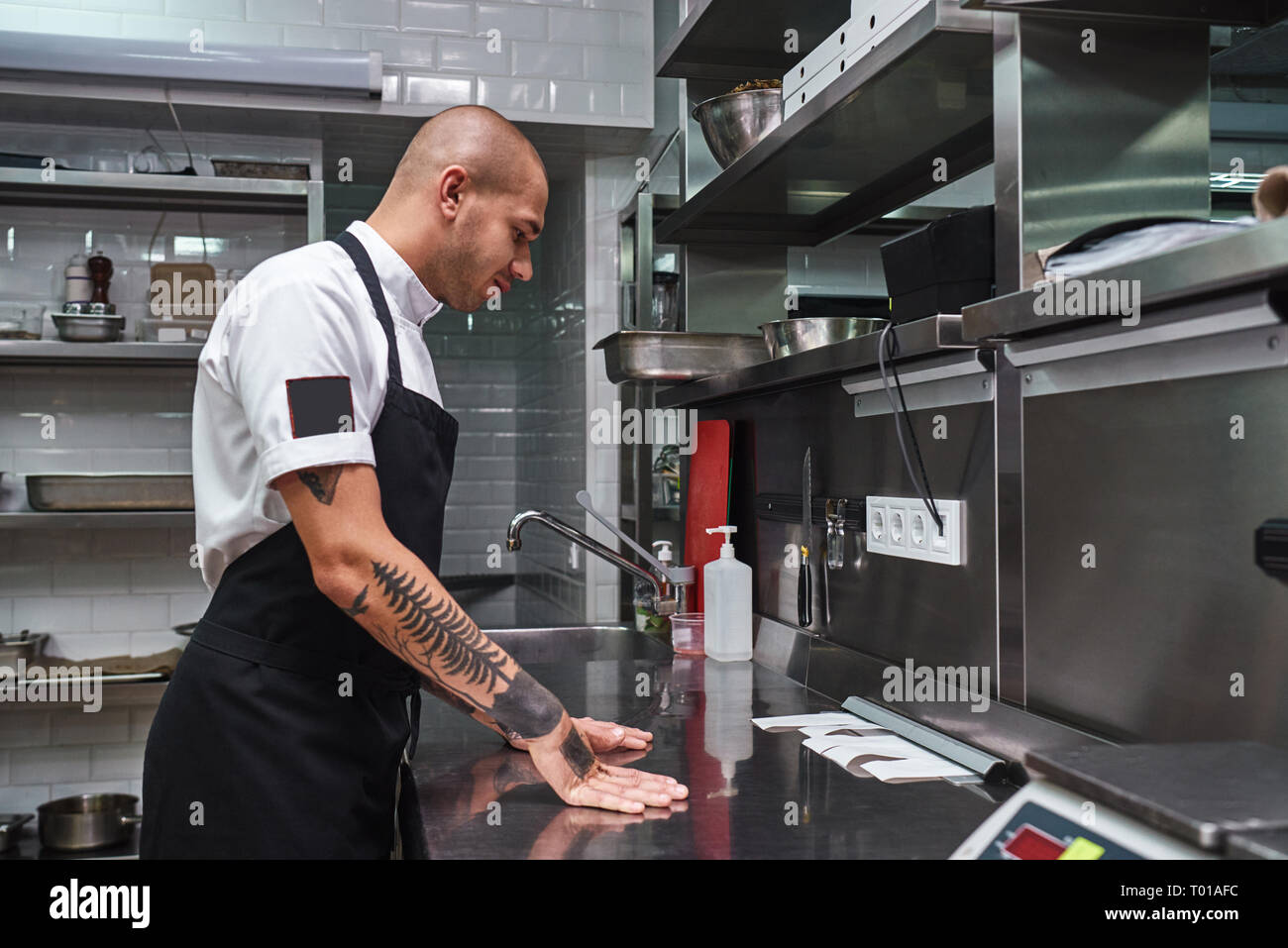 Let's start. Young bald male chef with beautiful tattoos on his arms ...
