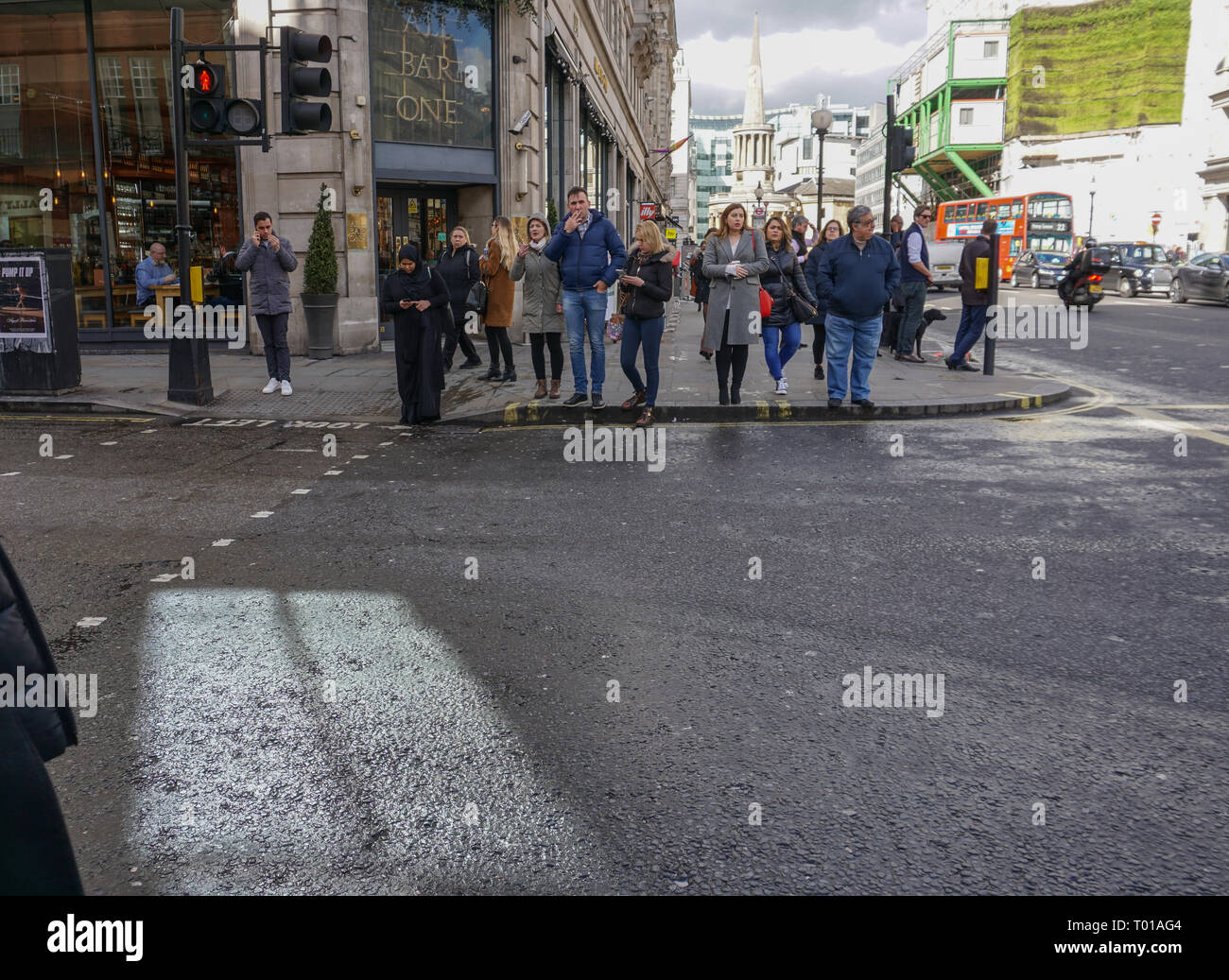 a group of pedestrians waiting to cross at a busy London intersection ...