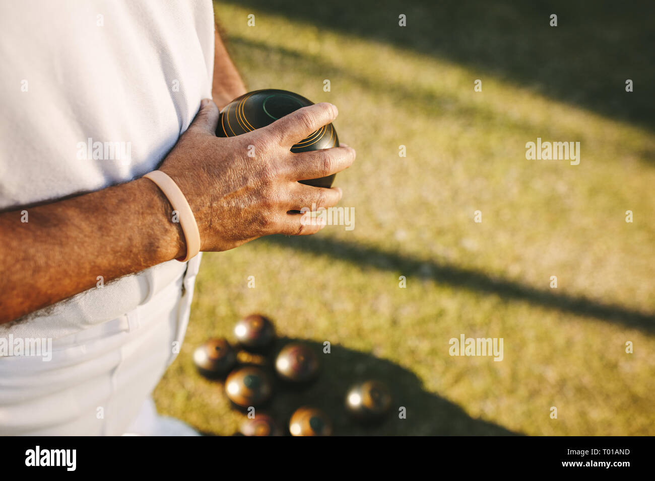 Man standing in a park playing boules on a sunny day. Person playing ...