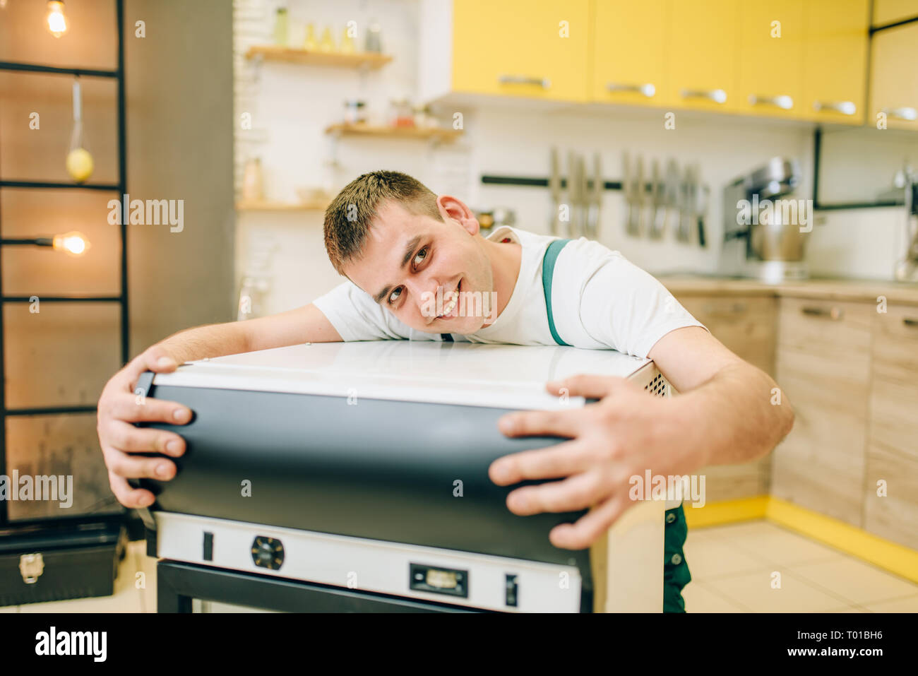 Worker in uniform hugs refrigerator at home Stock Photo - Alamy