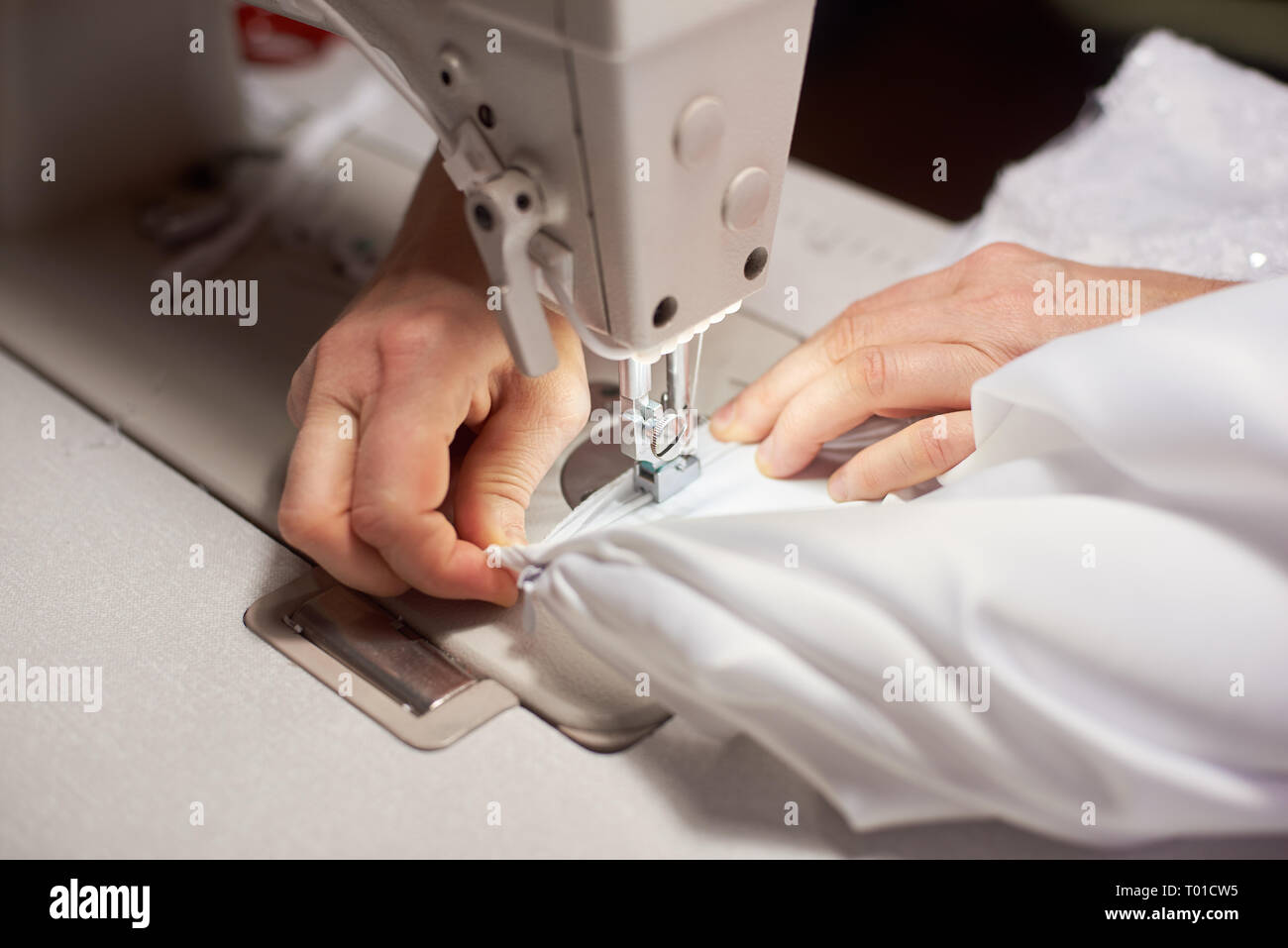 Female hands stitching white fabric on professional manufacturing ...