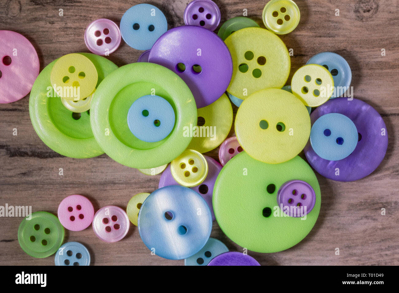 pile of pastel coloured buttons on a wooden background Stock Photo - Alamy