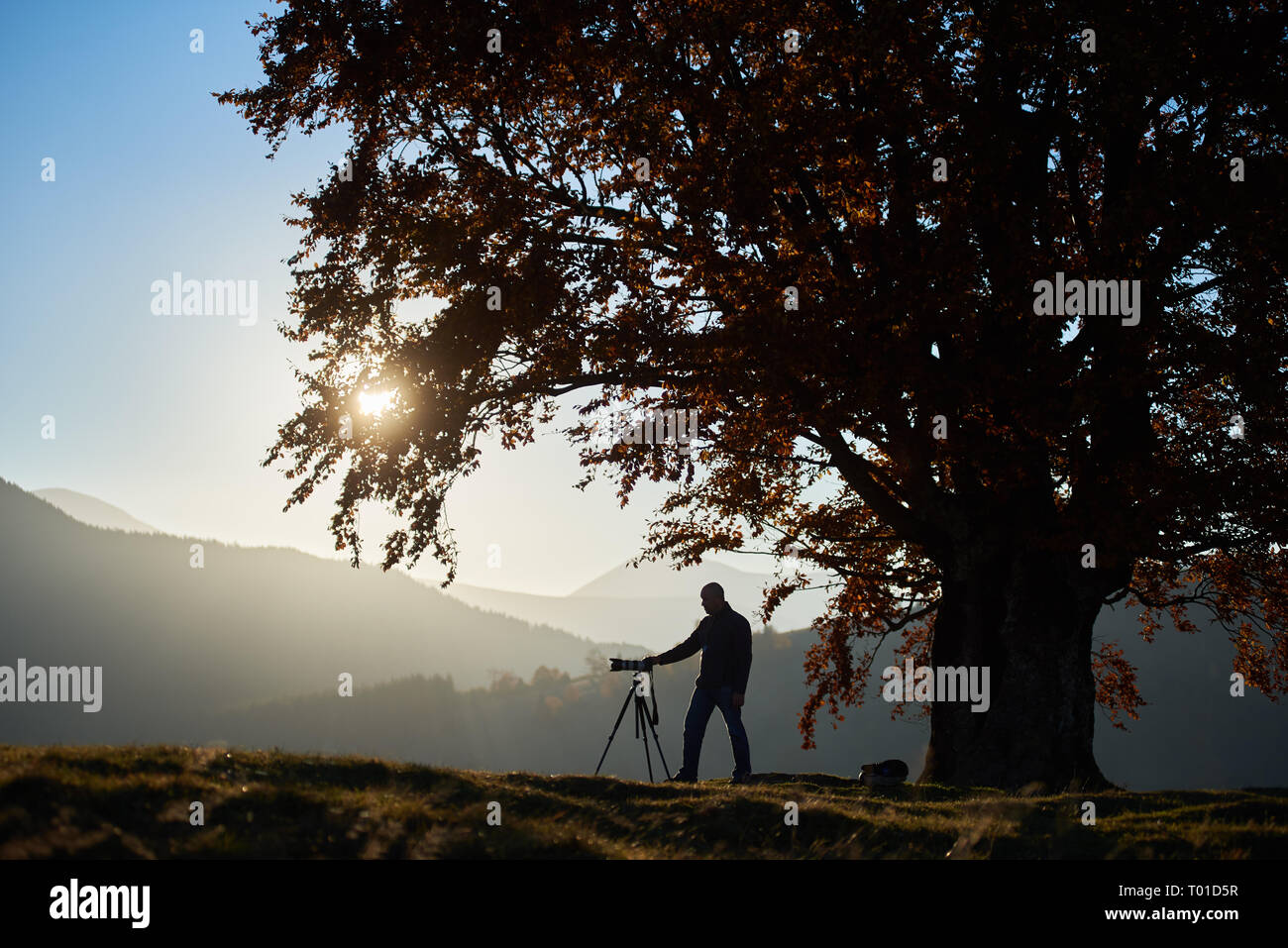 Male tourist photographer with tripod and professional camera standing ...