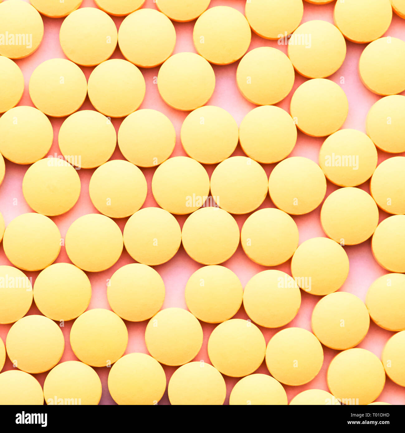 Small yellow pills on a pink background close-up Stock Photo - Alamy