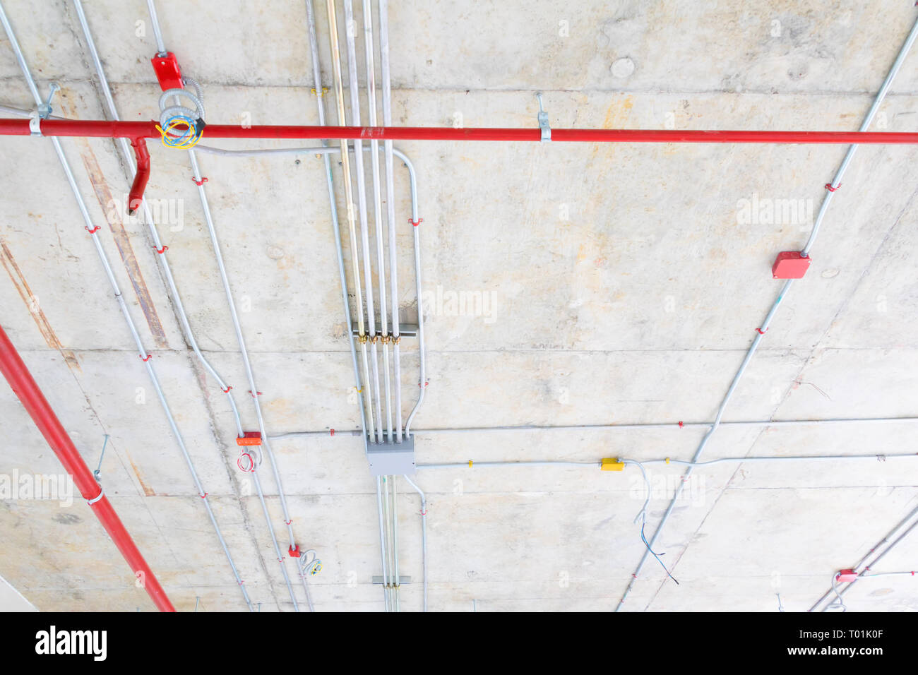 Metal pipes in Construction and fire sprinkler on red pipe are hanging ...