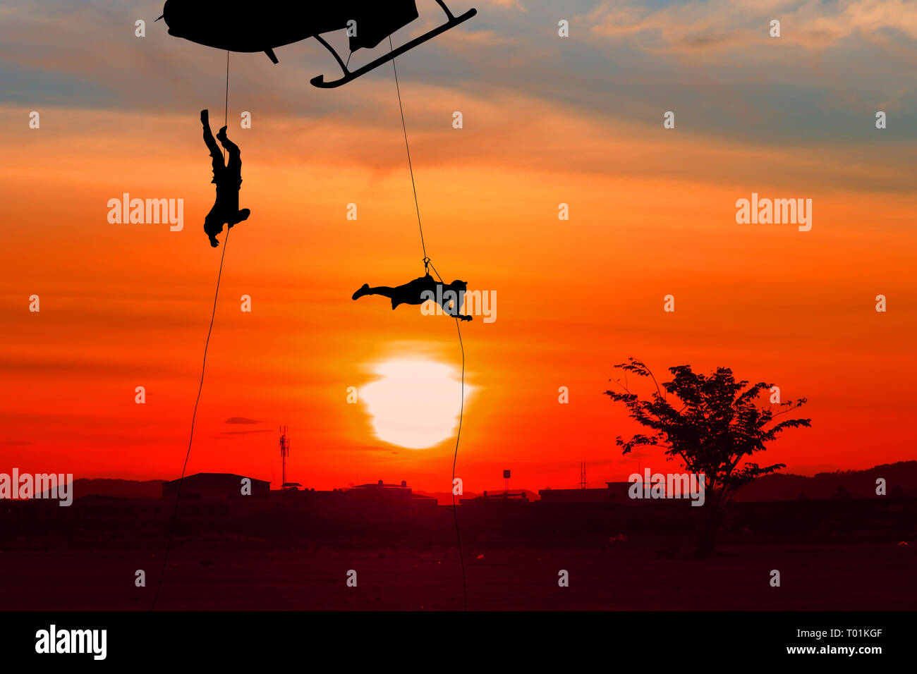 Silhouette Soldiers rappel down to attack from helicopter in blue sky ...