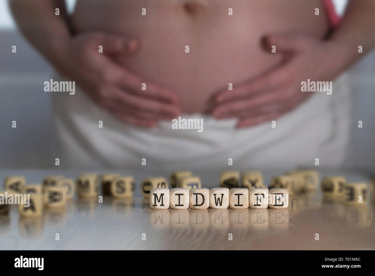 Word MIDWIFE composed of wooden letters. Pregnant woman in the ...