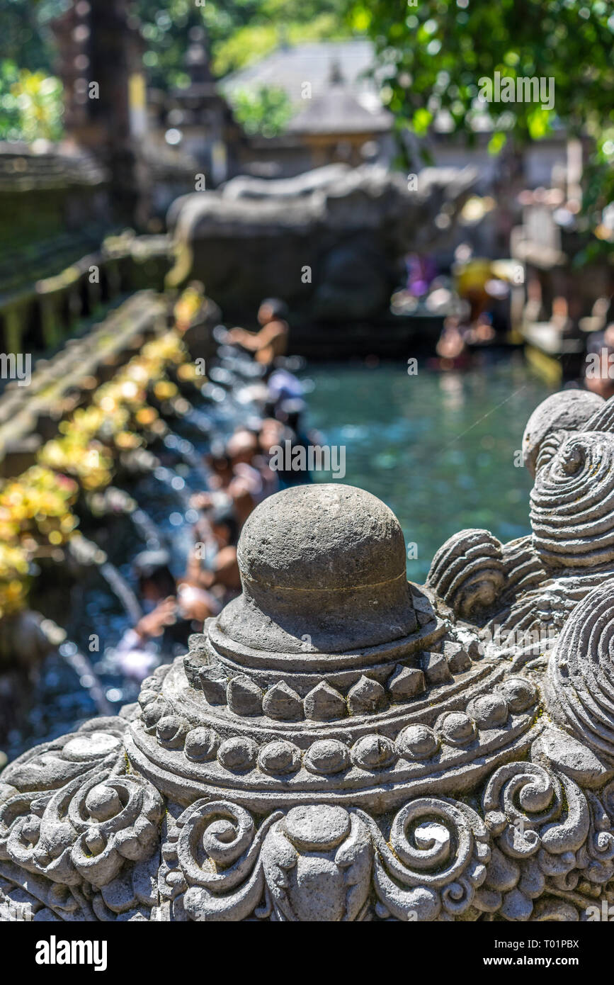 Detail of Guardian Sculpture of Pura Tirta Empul temple. Blurry people ...