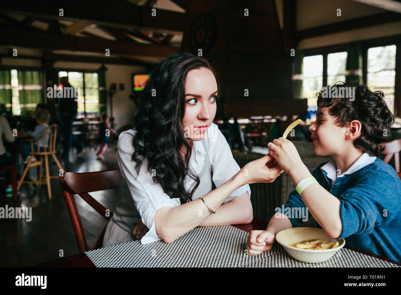 Mother and son eating fries in restaurant. Funny family dinner Stock ...