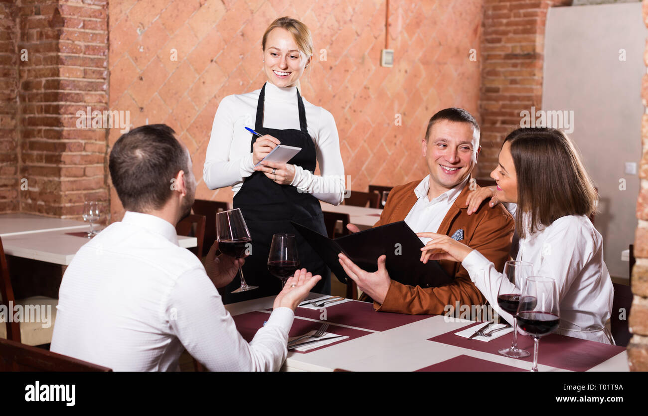 Adult female waiter writing down order from visitors in country ...