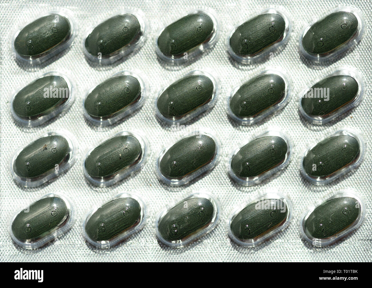 Rows of green medicine tablets in macro closeup with their tin blister ...
