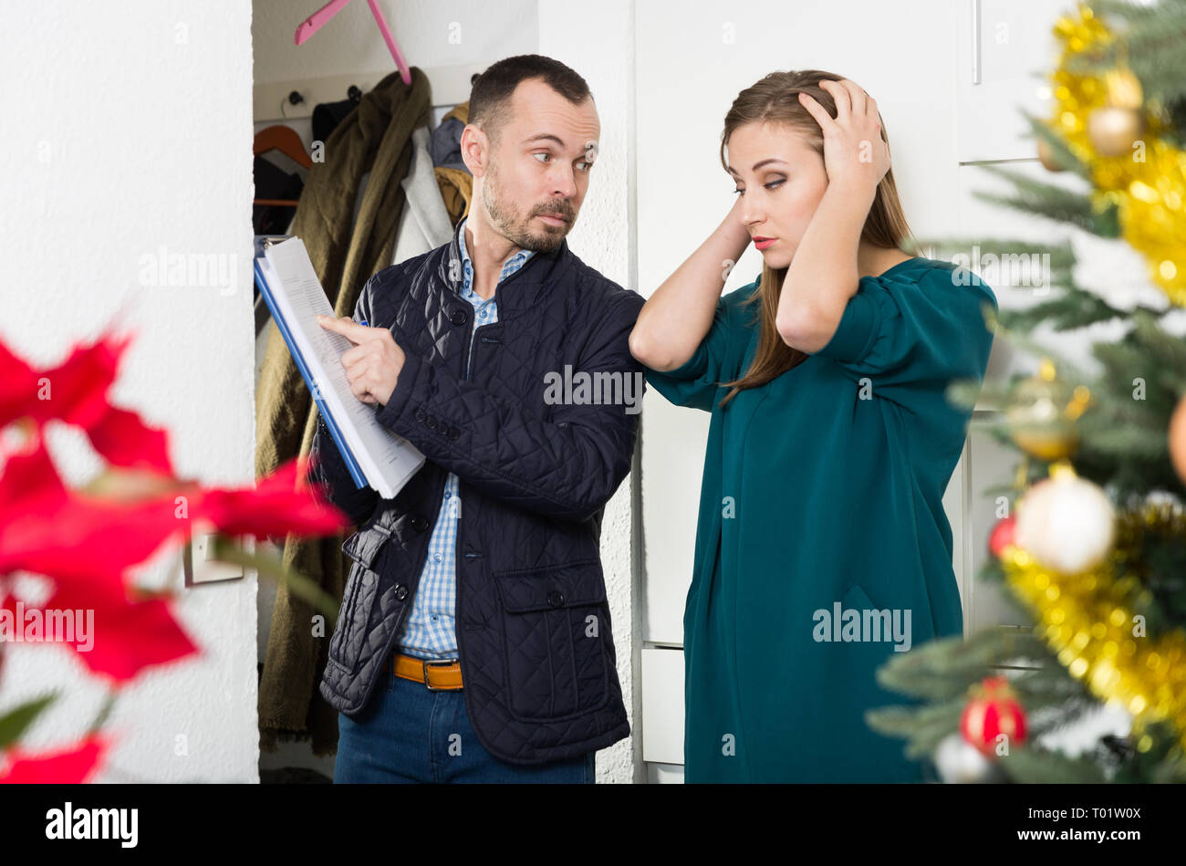 Debt collector and sad young woman with overdue payment at doorway ...