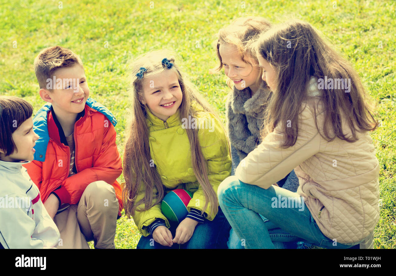 Group of happy positive children laughing and chatting in spring park ...