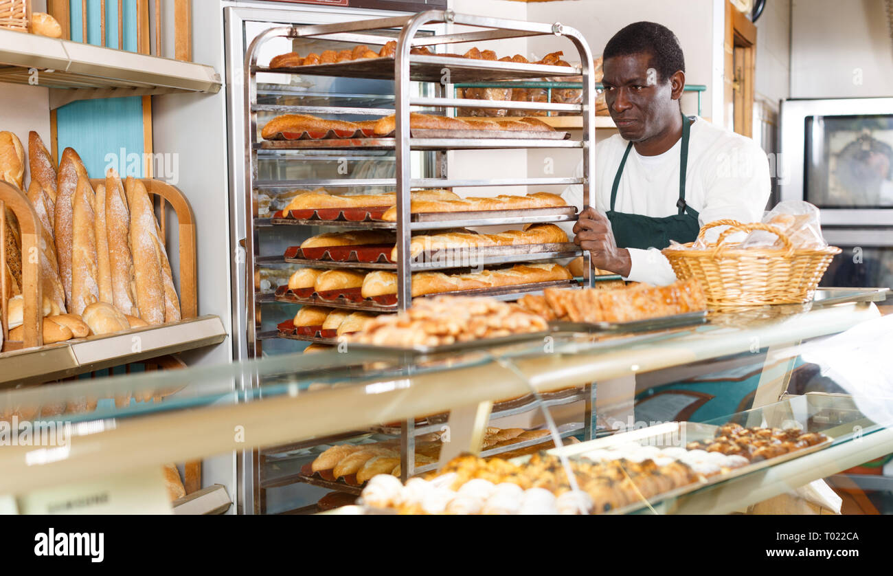 Skillful African American baker working in small bakery, carrying fresh ...