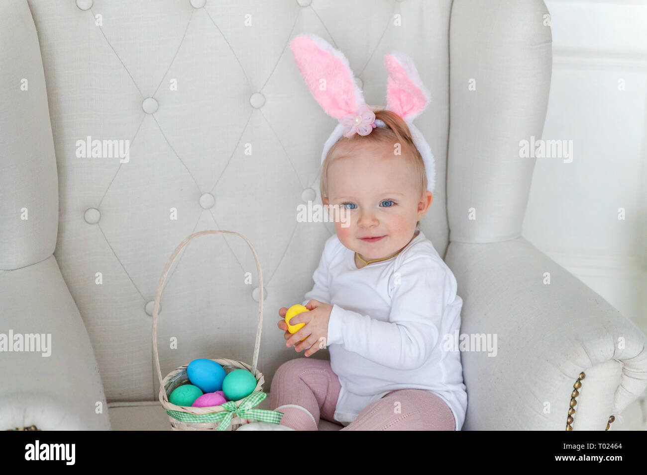 Little child girl wearing bunny ears on Easter day. Girl holding basket ...