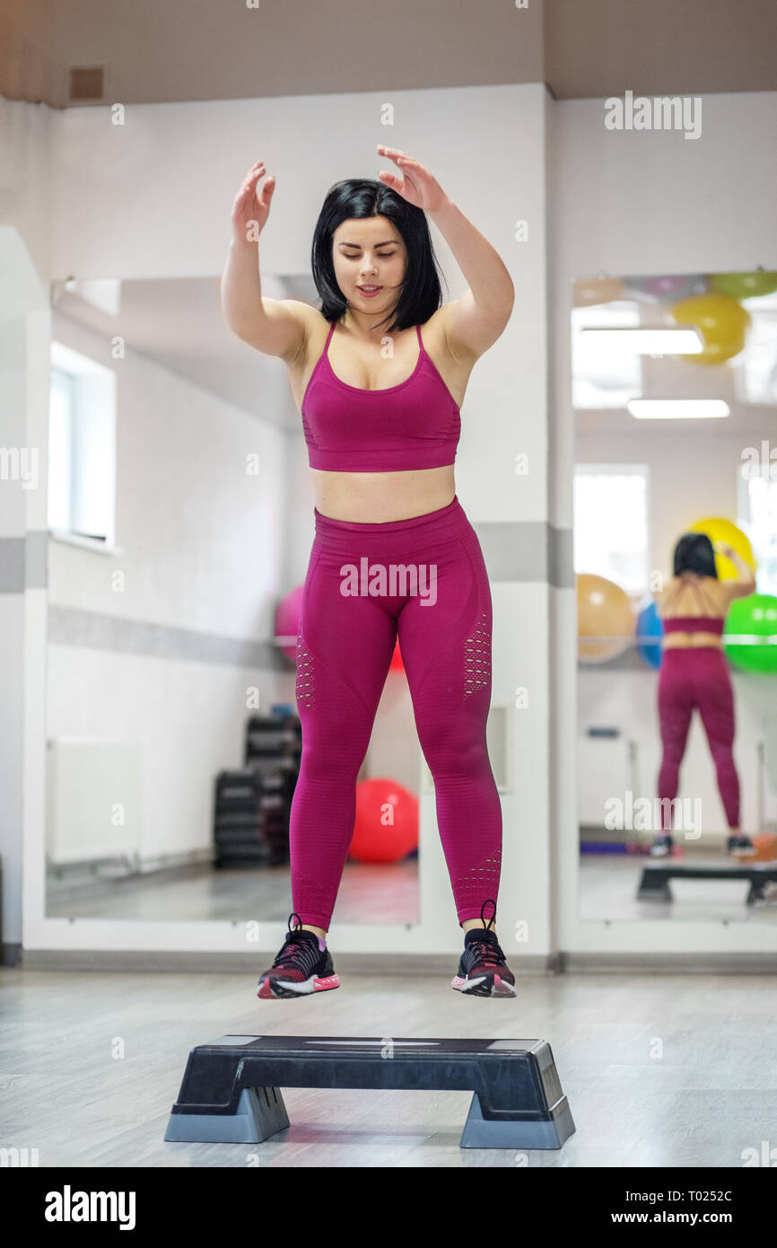 Athletic young girl practicing on the stepper in the gym. The concept ...