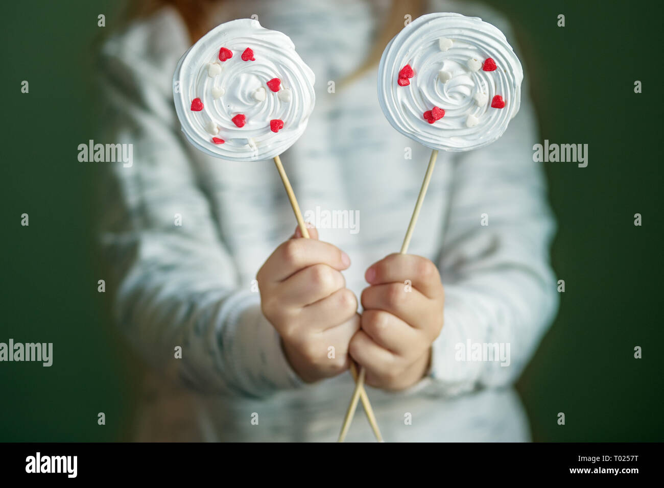 Delicious meringue sweets with hearts in children's hands. The concept ...