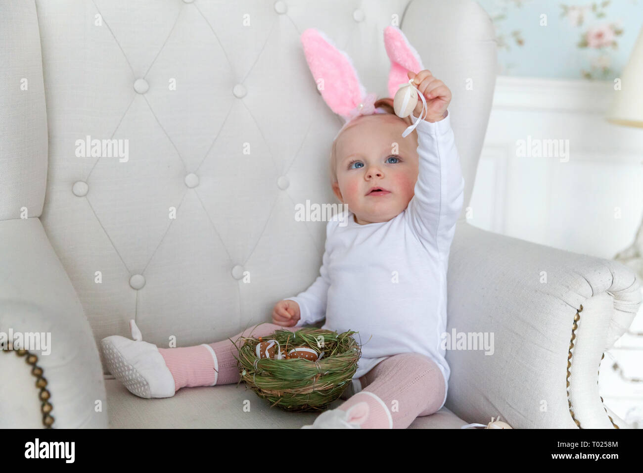 Little child girl wearing bunny ears on Easter day. Girl holding basket ...