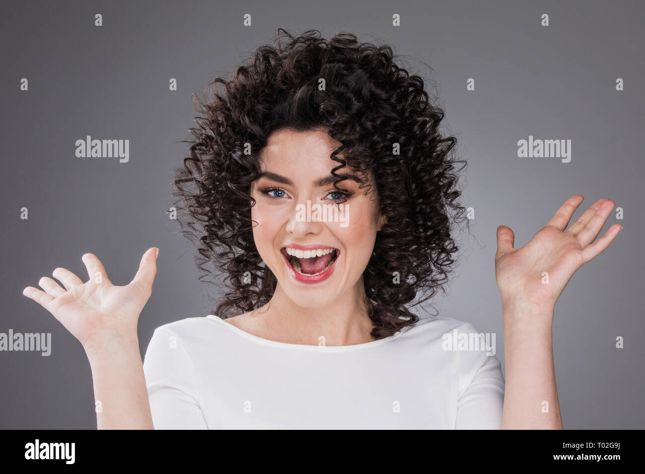 Surprised young woman shouting over gray background. Looking at camera ...