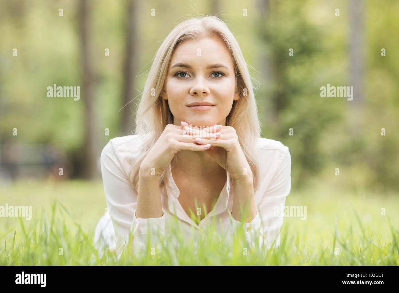 Blonde Pretty Girl Laying On The Grass In Spring Park And Smiling Stock