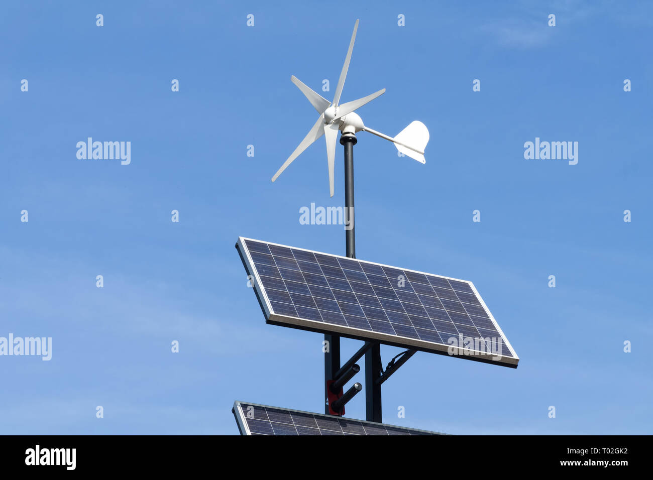 Small wind power generator and set of Solar panels agains blue sky ...