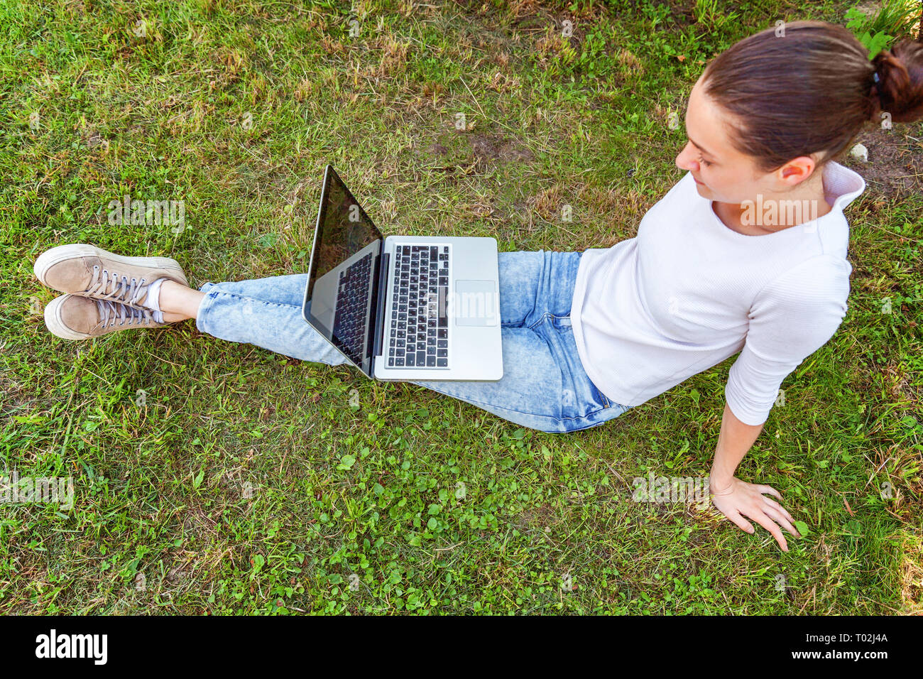 Freelance business concept. Woman legs on green grass lawn in city park ...