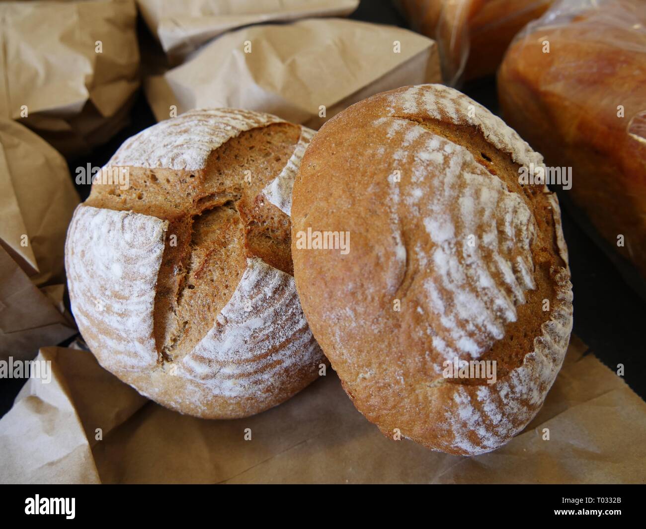 Homemade hard round wheat bread displayed with paper bags in the ...