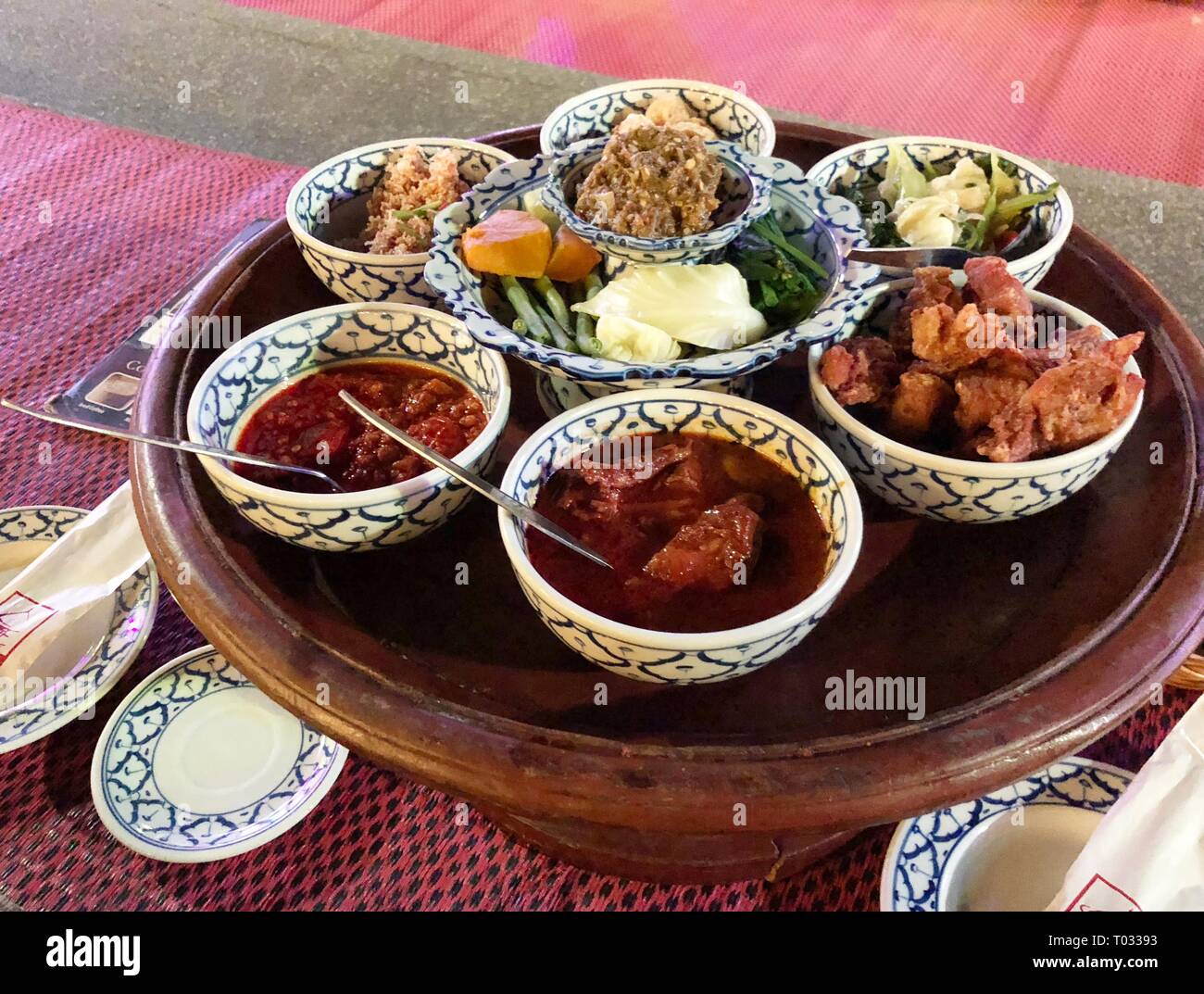 Round wooden tray of assorted Thailand delicacies and favorites served ...