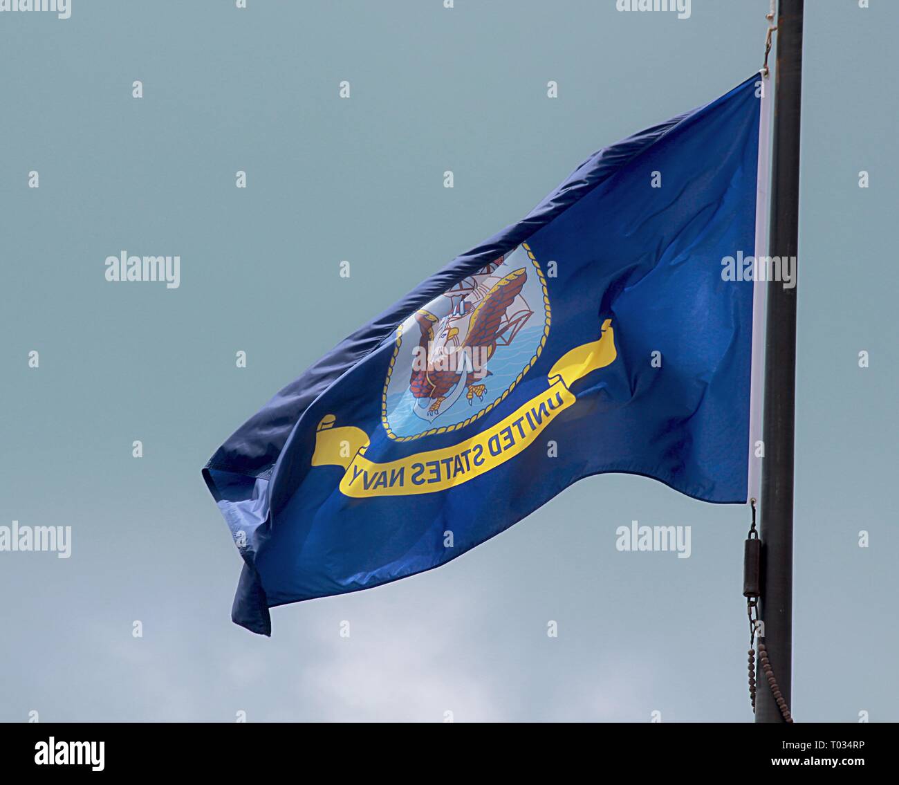 United States Navy flag waving in the wind from a pole, with light blue ...