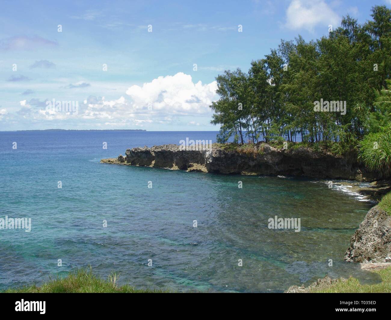 Clear blue and green waters with small coral formations and cliffs at a ...