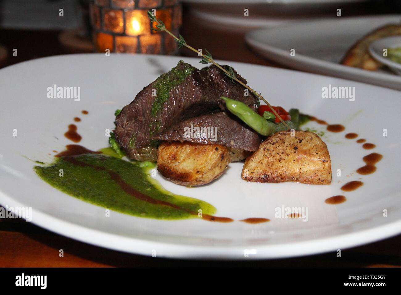 Medium rare steaks served with potatoes and greens in a round white ...