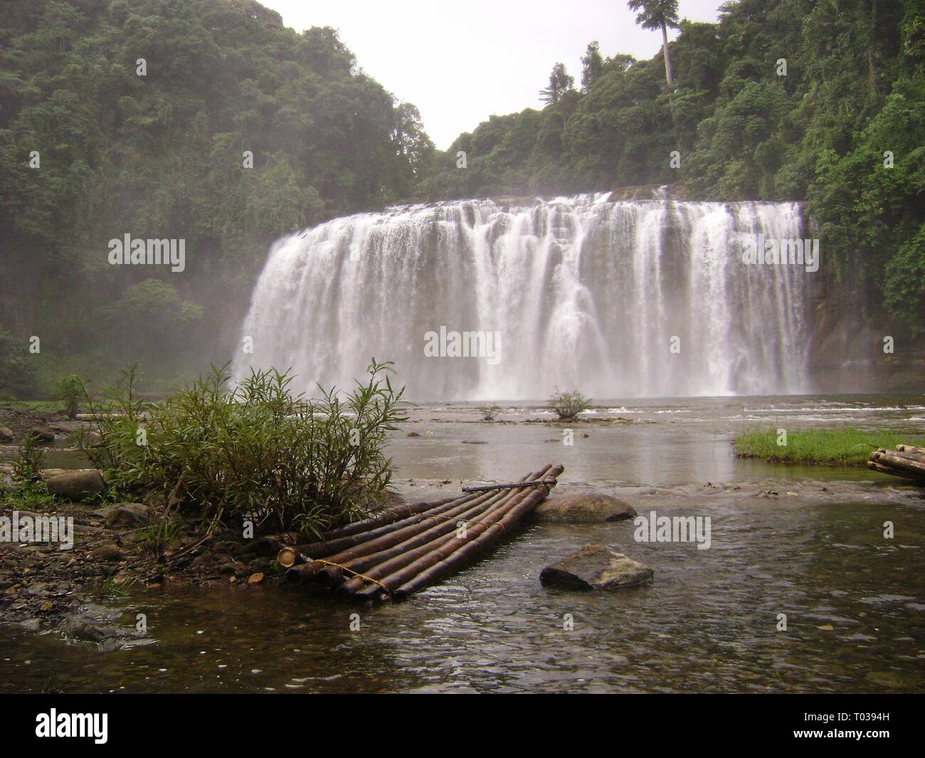 Front view of Tinuy-an Falls with a bamboo raft in the foreground ...