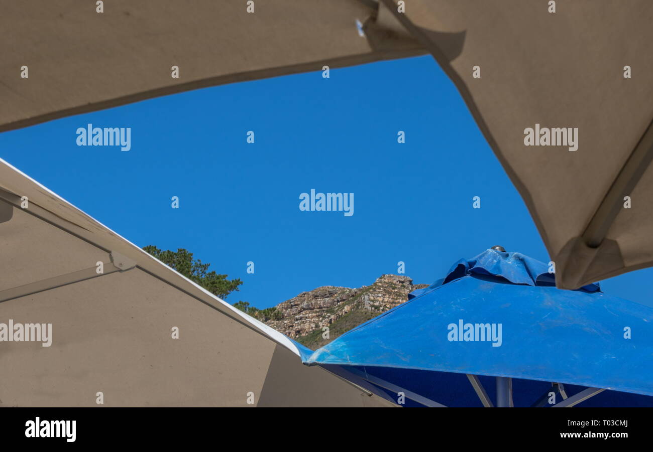 A glimpse of blue sky and a mountain from below umbrellas image with ...