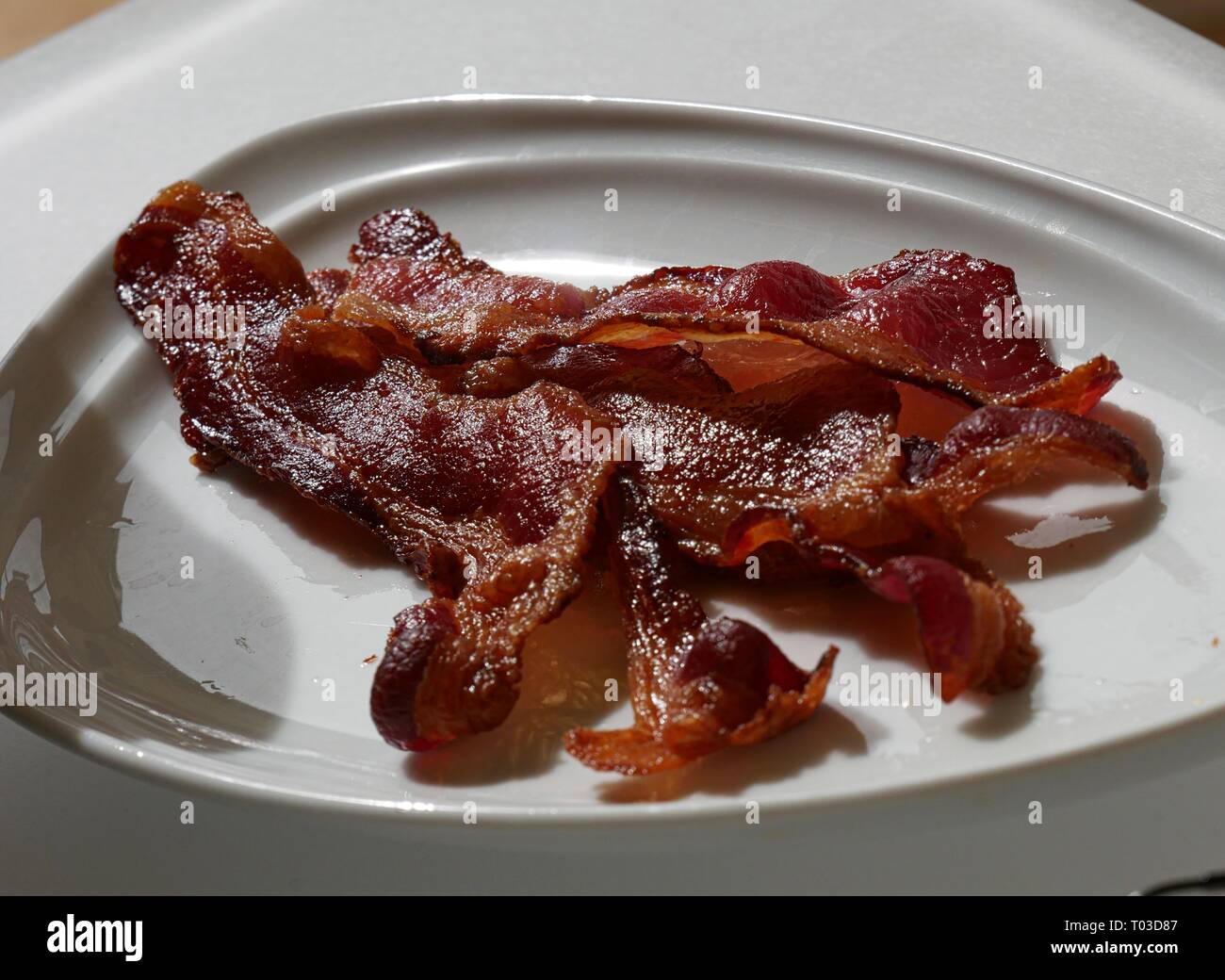 Fried bacon strips on a white round plate Stock Photo - Alamy