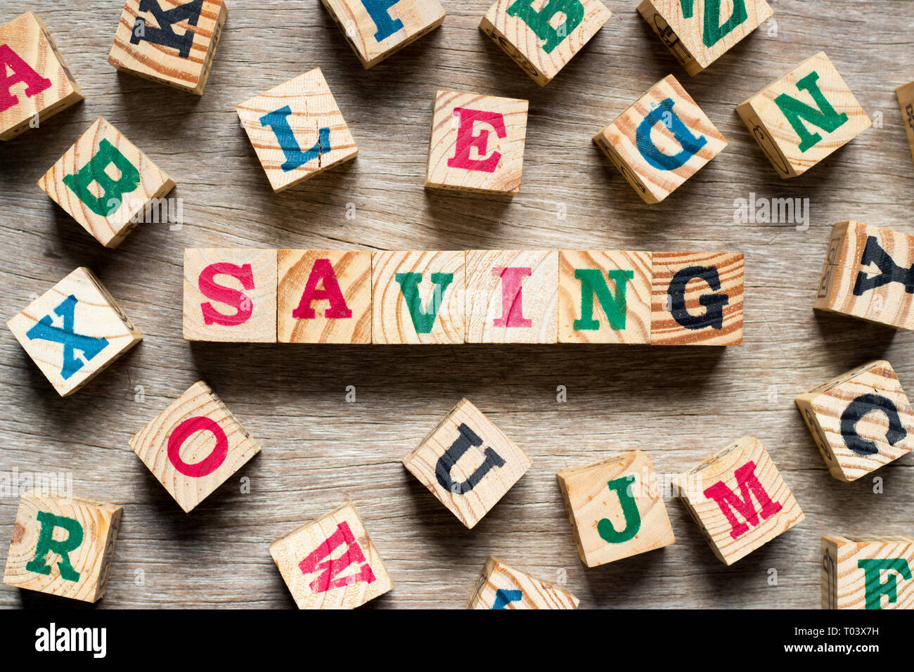 Letter block in word saving with another alphabet on wood background ...