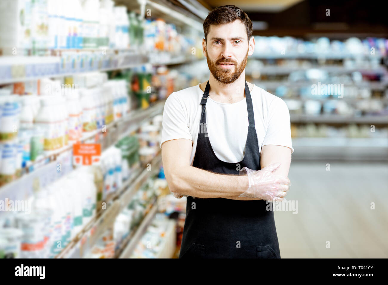 Portrait of a handsome shop worker or milkman standing near the selves ...