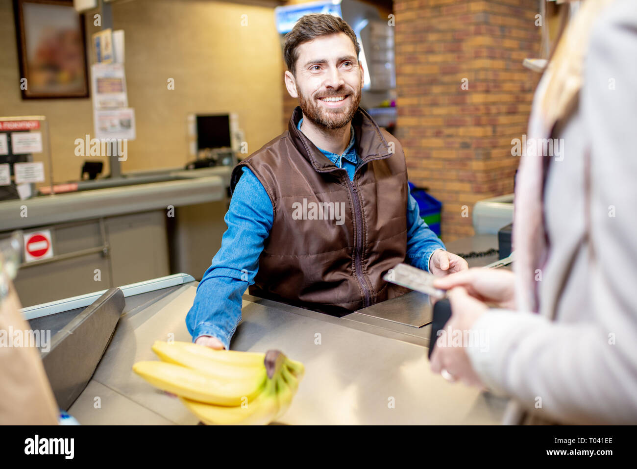 Portrait of a happy and cheerful man as a cashier loving his job ...