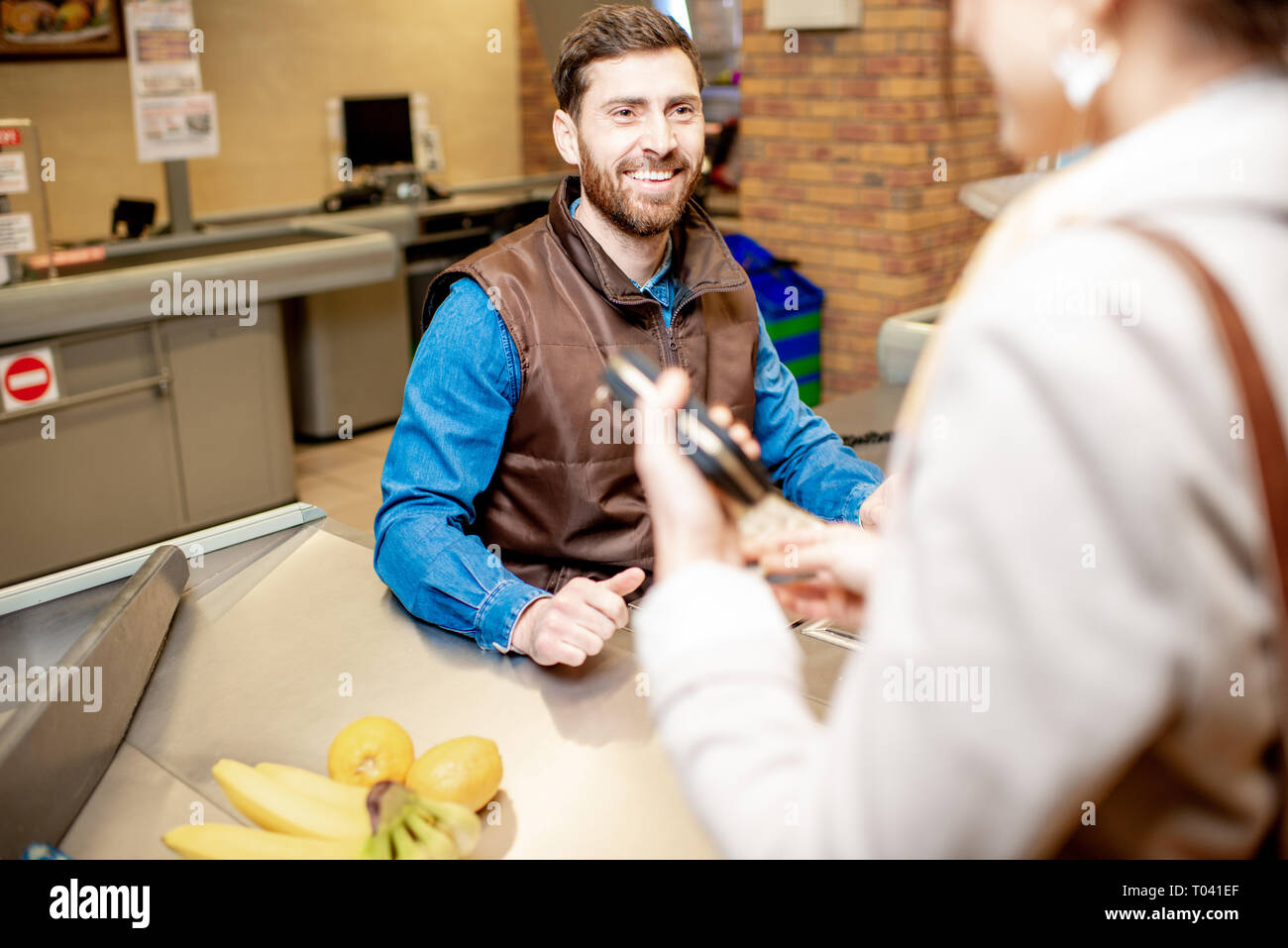 Portrait of a happy and cheerful man as a cashier loving his job ...
