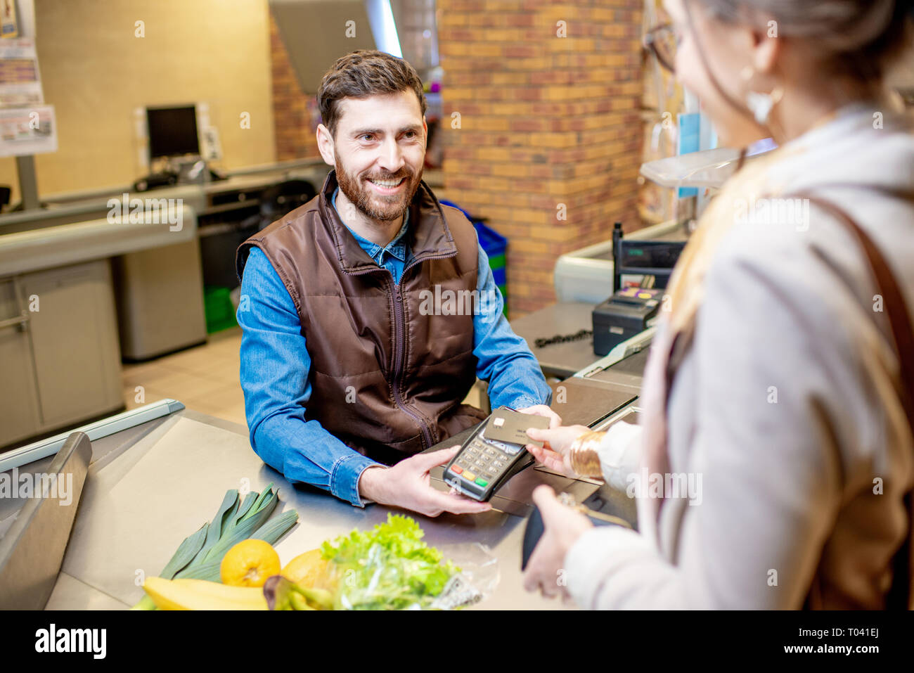 Young woman customer paying with a credit card for shopping at the cash ...